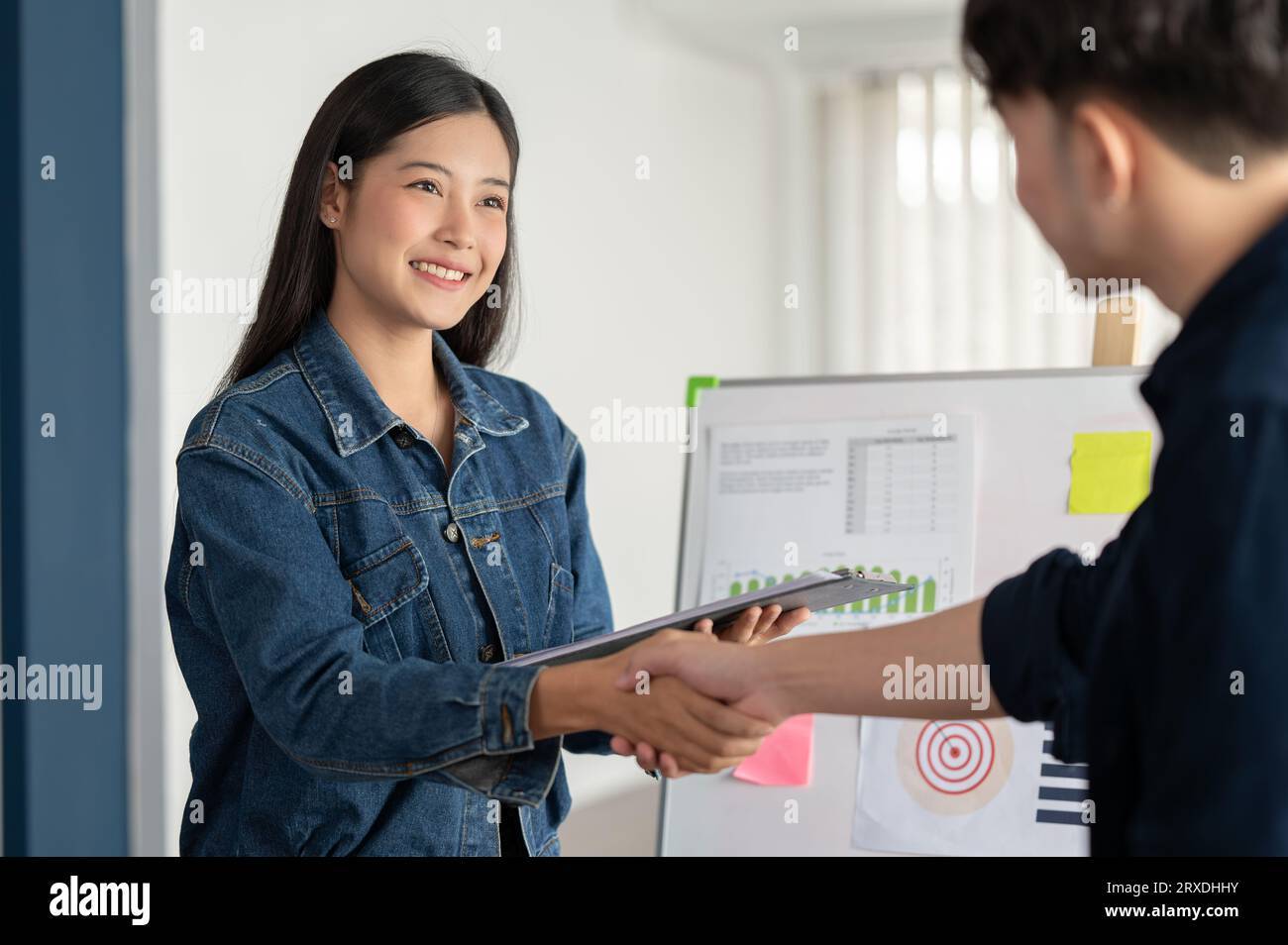 A confident and beautiful young Asian businesswoman is shaking her hand ...