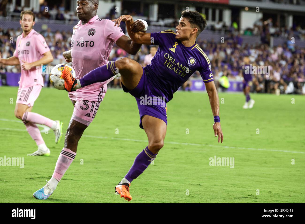Orlando City forward Ramiro Enrique, right, kicks the ball as he is ...