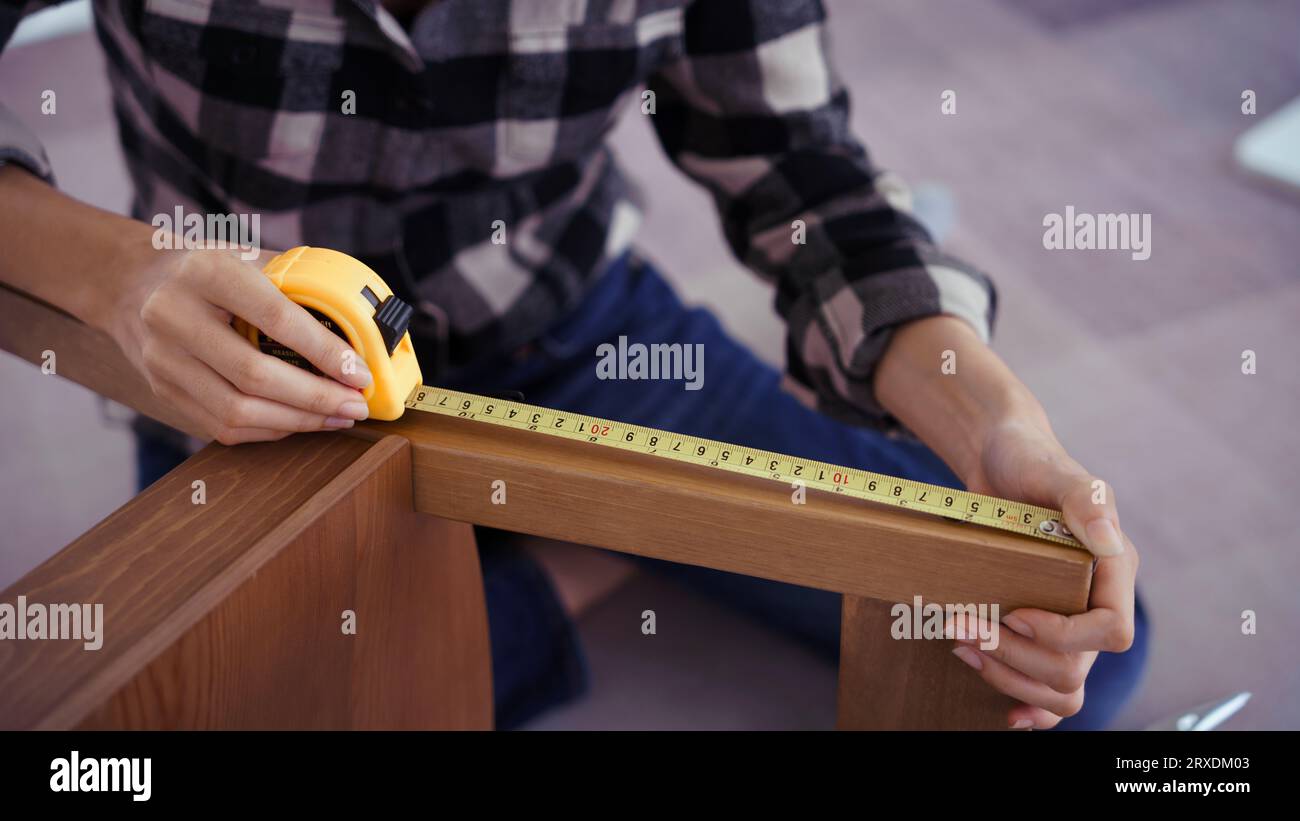 Women measuring length of chair with measure tape while assembling and ...