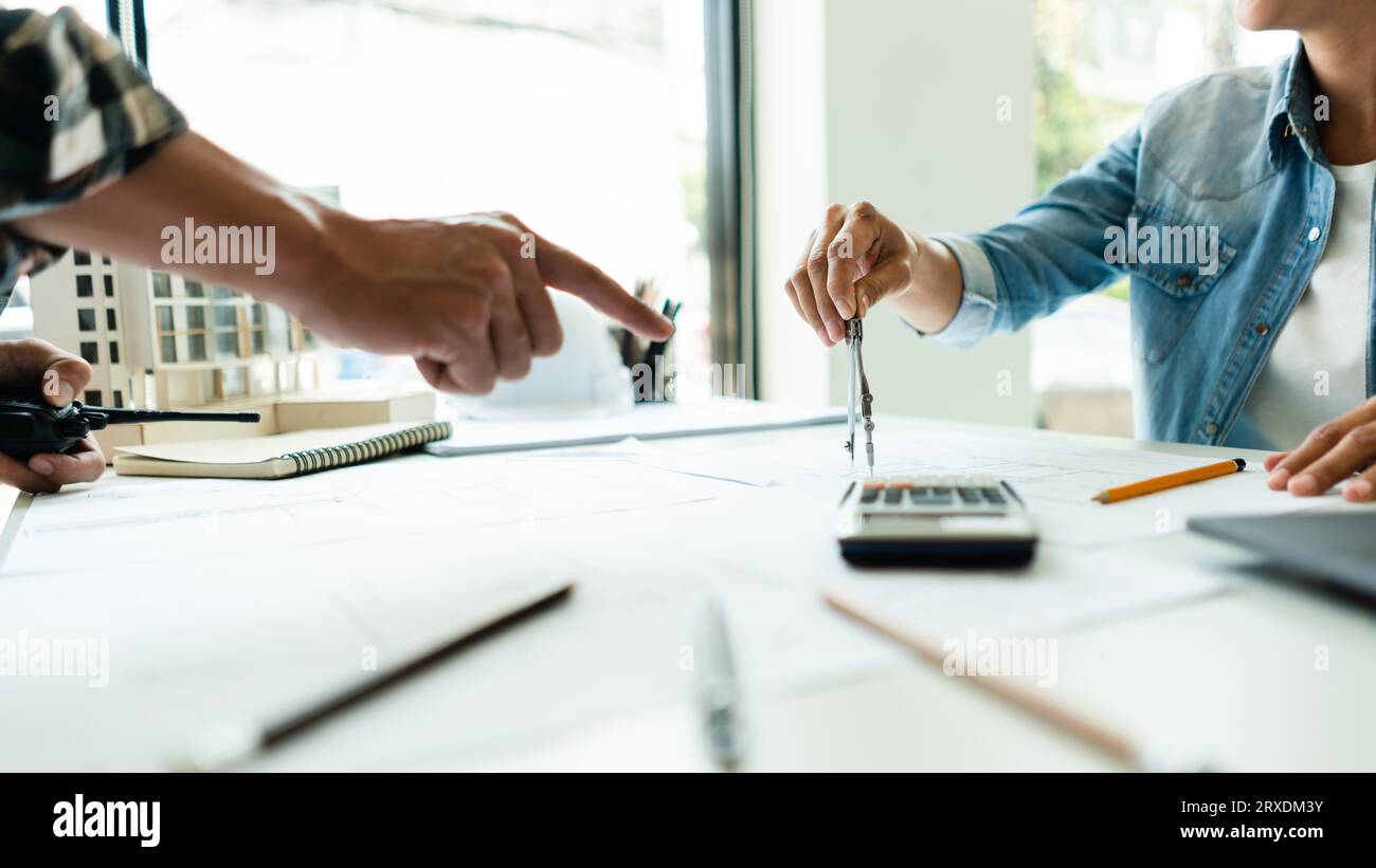 Two engineer working and using geometry compass to drawing construction ...
