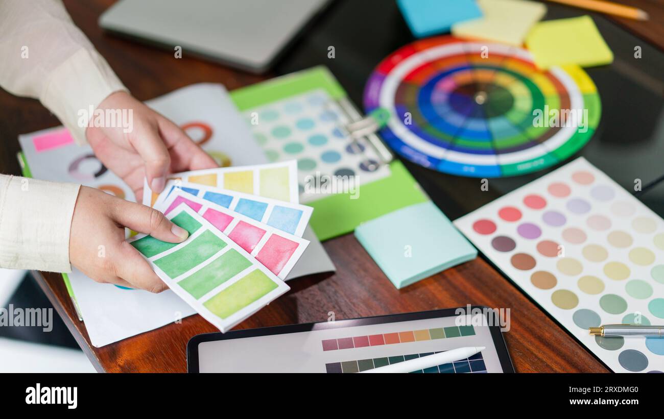 Creative graphic designer holding color swatch to comparing color on ...