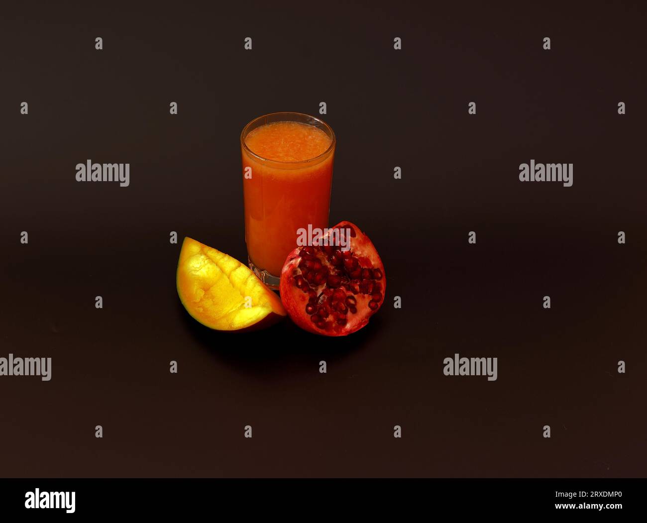 A glass of fresh fruit juice on a black background, next to a ripe ...