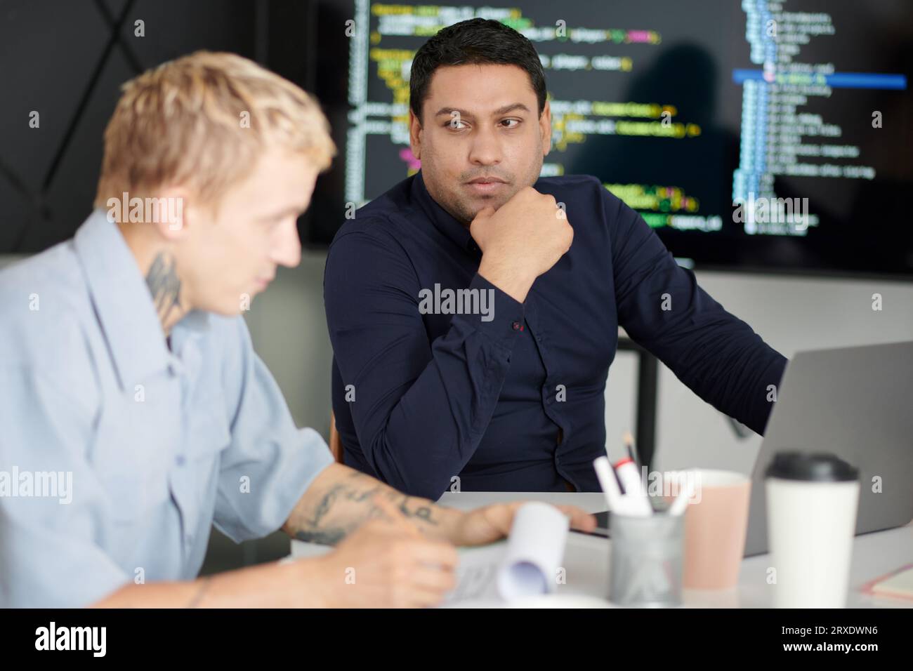 Pensive project manager listening to developer explaining new features ...