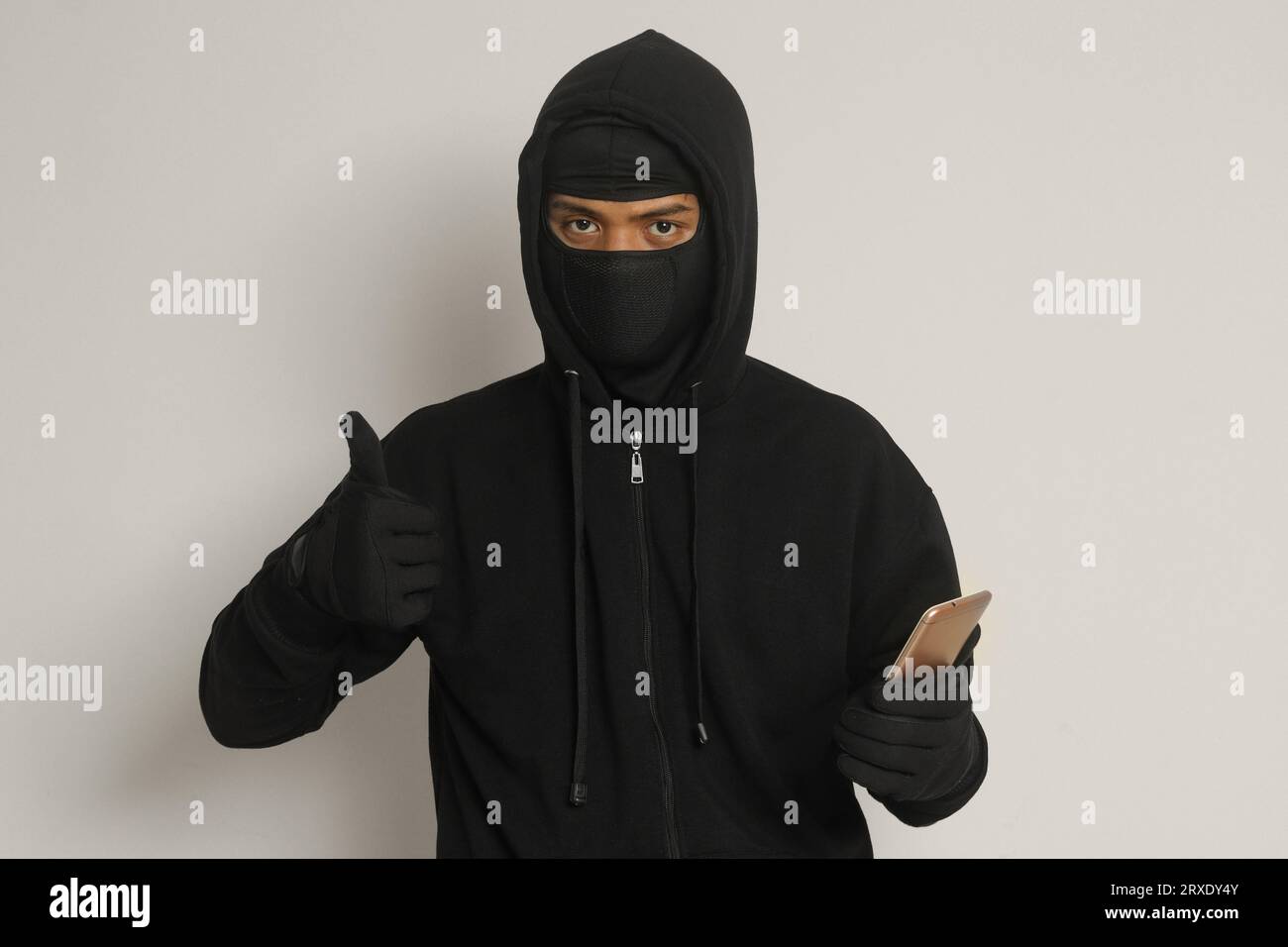 Portrait of mysterious man wearing black hoodie and mask doing hacking ...
