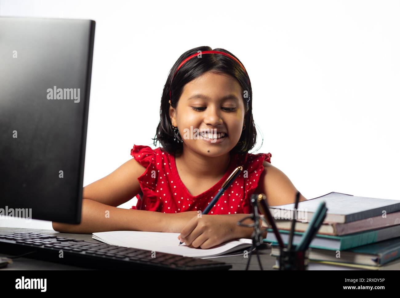 A pretty beautiful Indian girl child studying with desktop computer at ...
