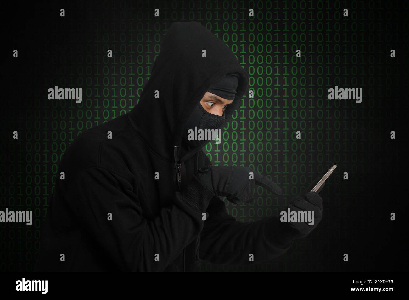 Portrait of mysterious man wearing black hoodie and mask doing hacking ...
