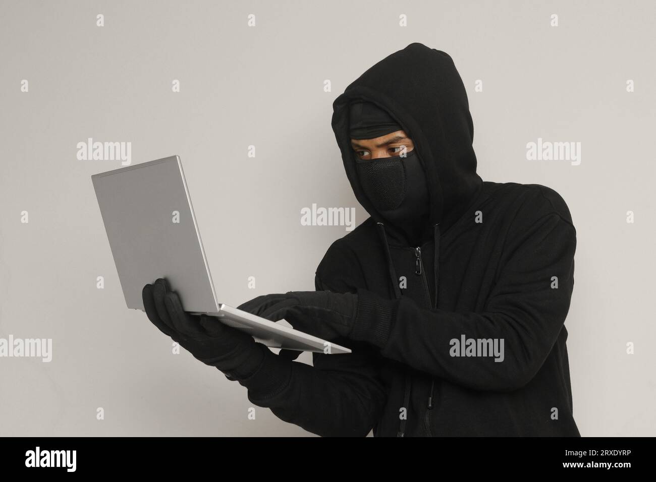 Portrait of mysterious man wearing black hoodie and mask doing hacking ...