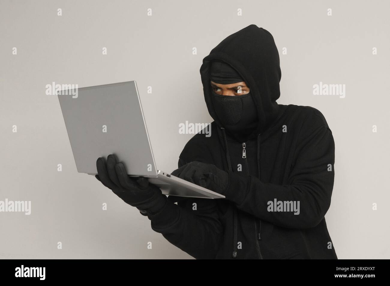 Portrait of mysterious man wearing black hoodie and mask doing hacking ...