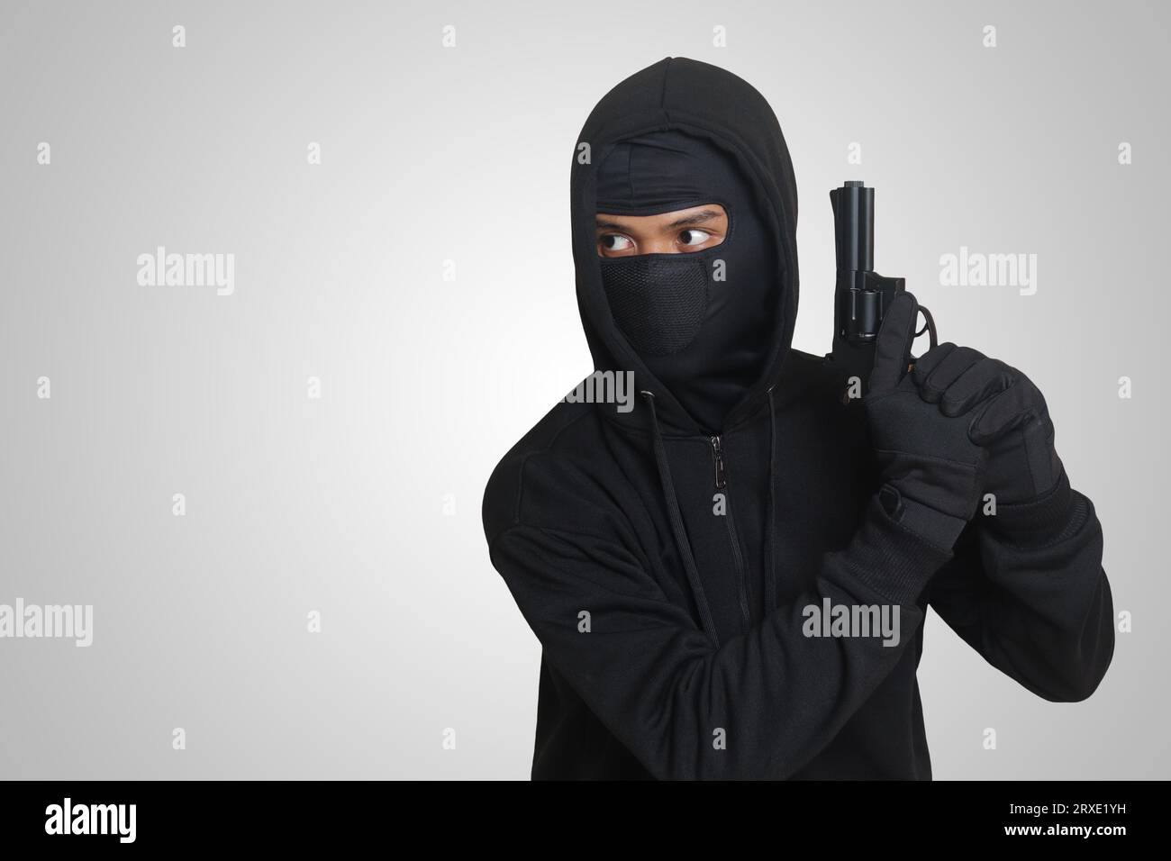 Mysterious man wearing black hoodie and mask holding a pistol, shooting ...