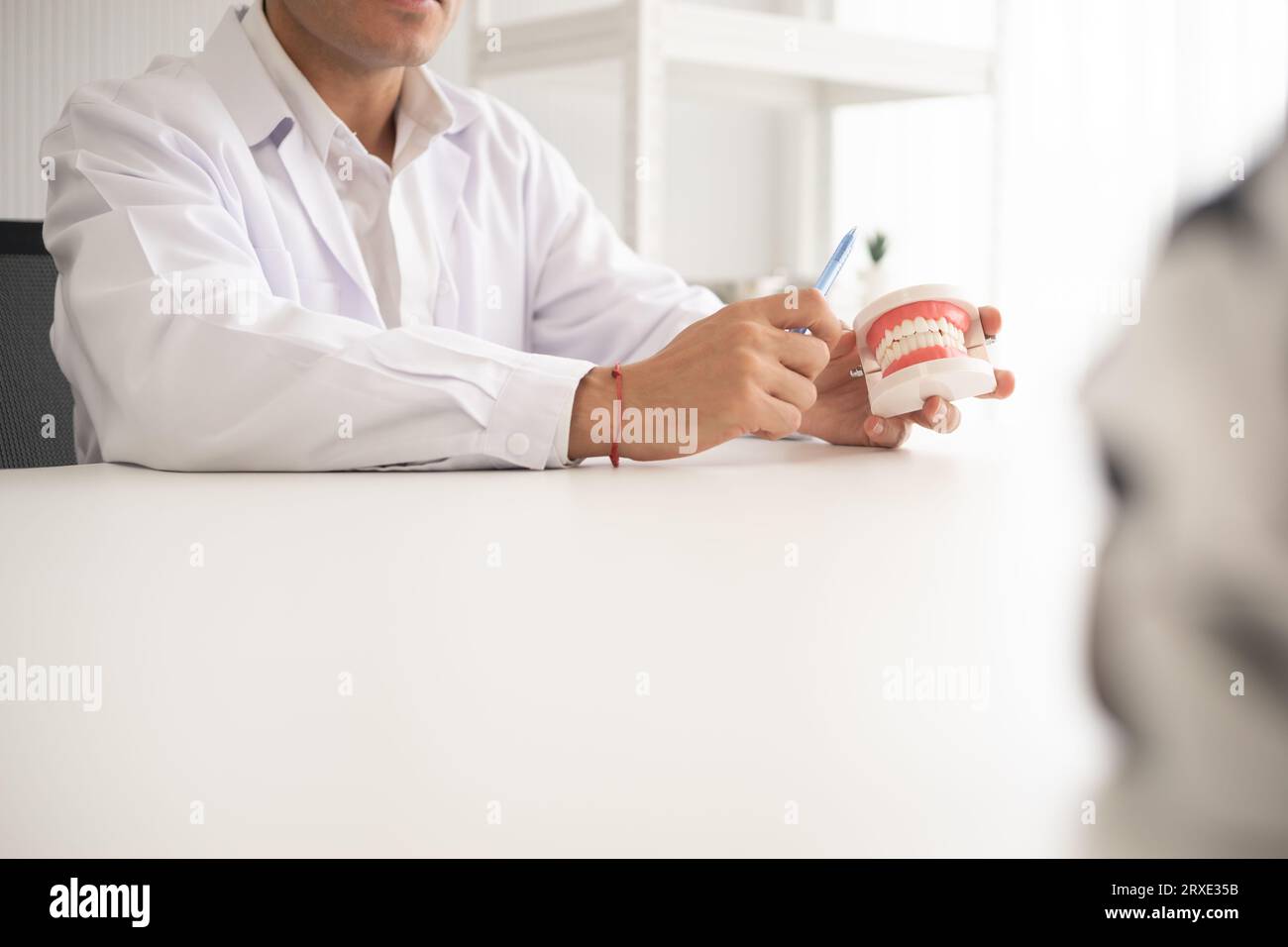 Hispanic dentist explaining to patient about teeth and how to brush ...