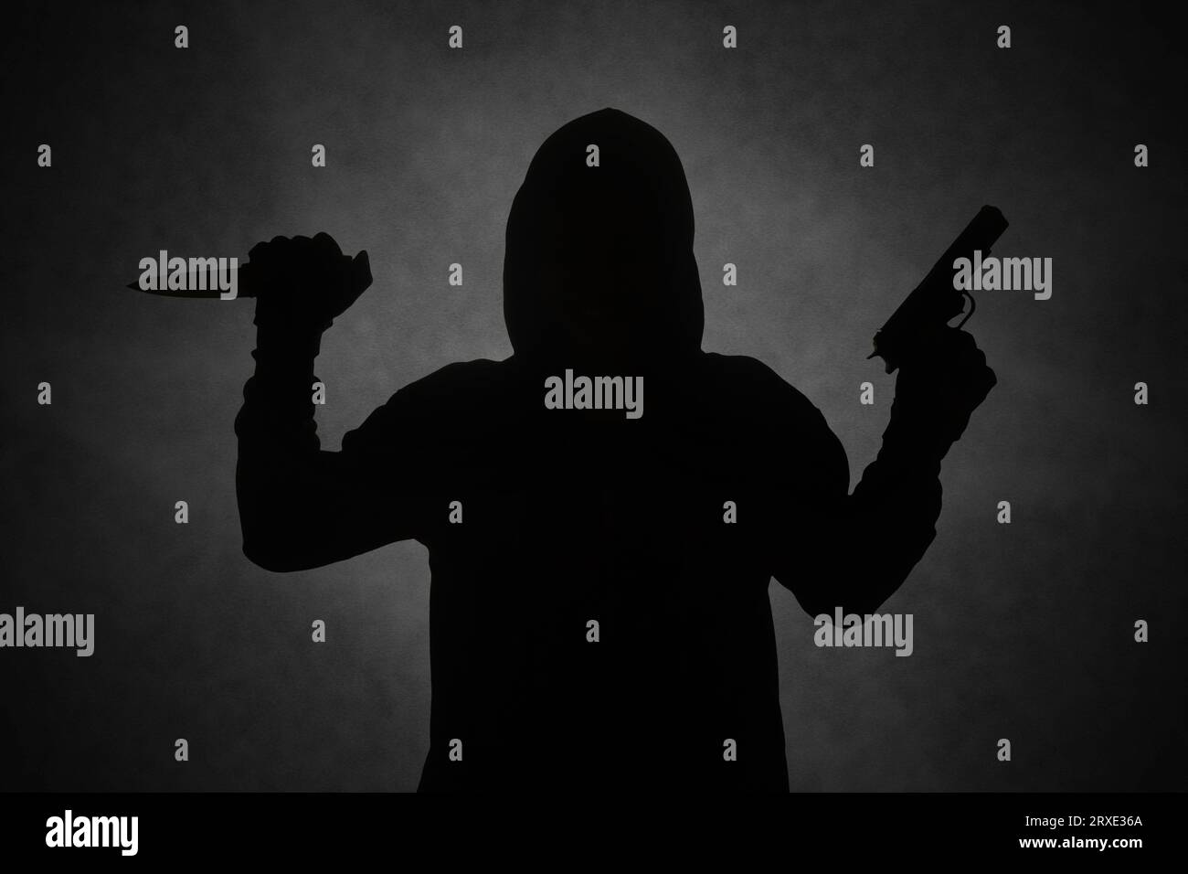 Mysterious Man Wearing Black Hoodie Holding A Pistol Shooting With A Gun While Holding A Knife