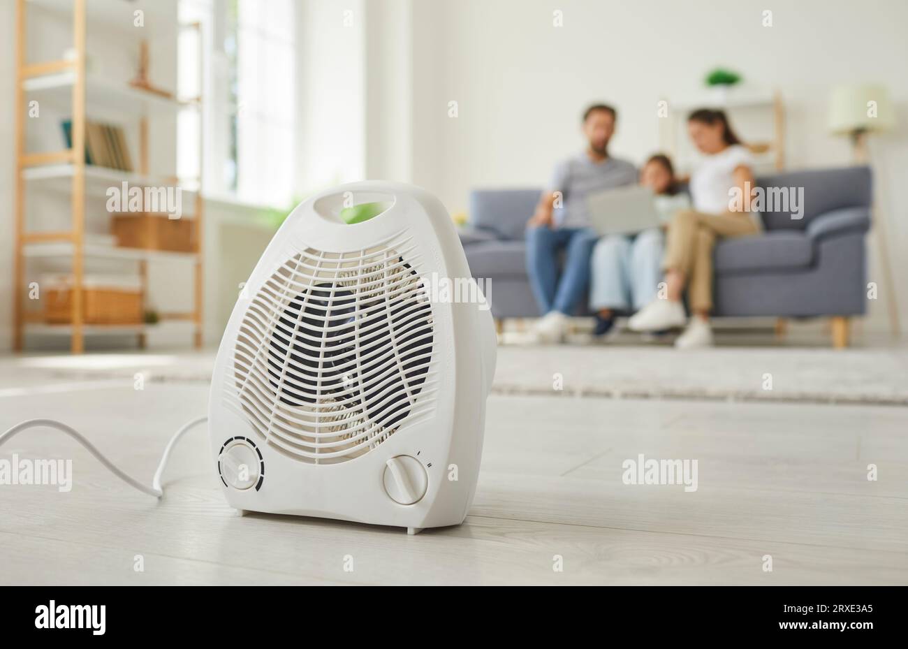 Portable electric fan heater on floor in living room, with family on ...