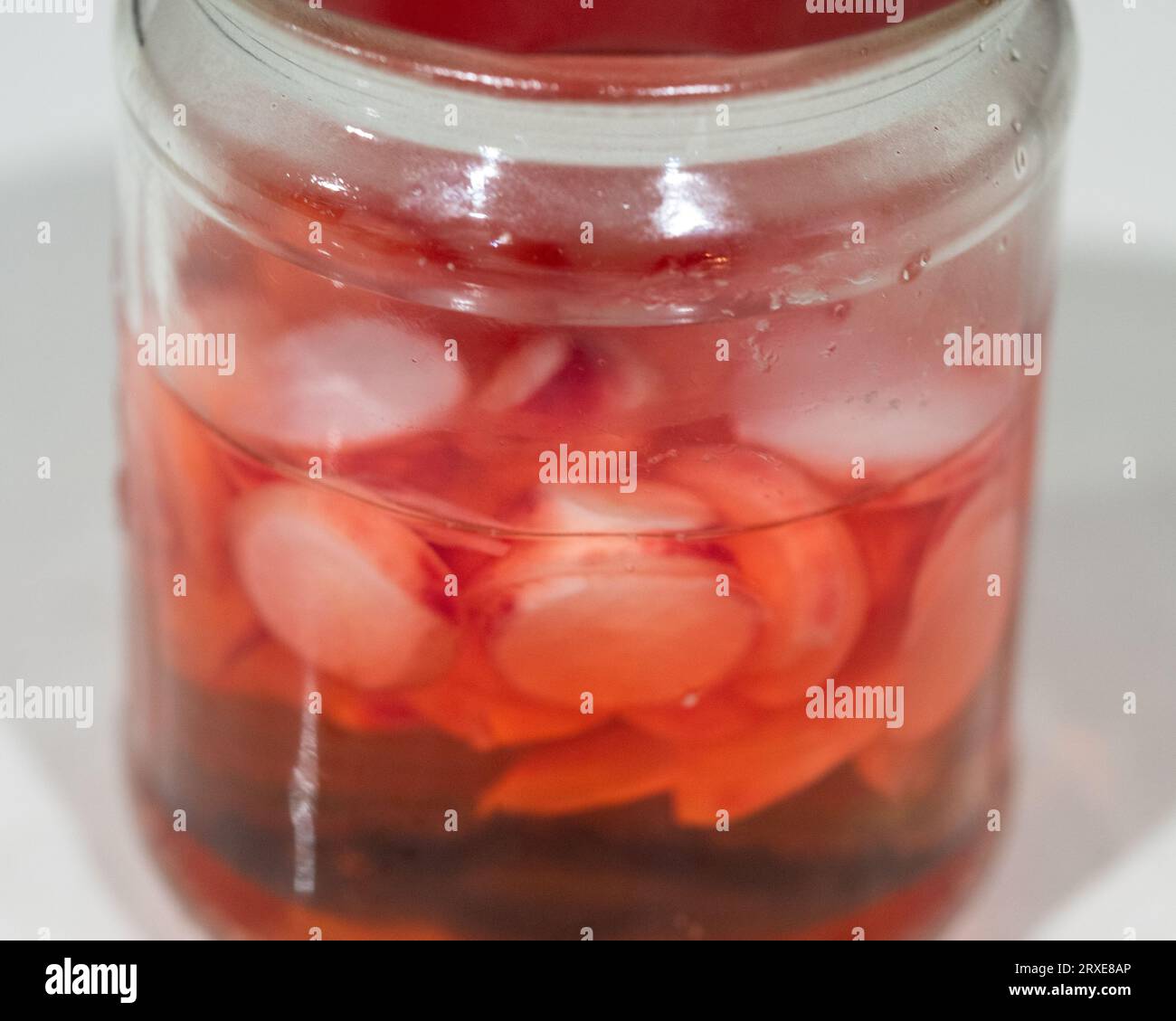 Pickled Radishes in a glass jar with brine liquid, red skin white flesh ...