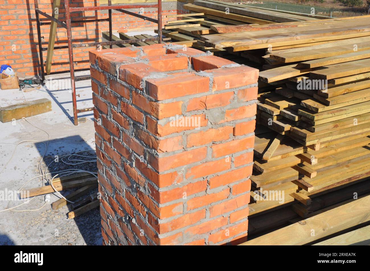 Building chimney from red bricks in unfinished house construction site ...