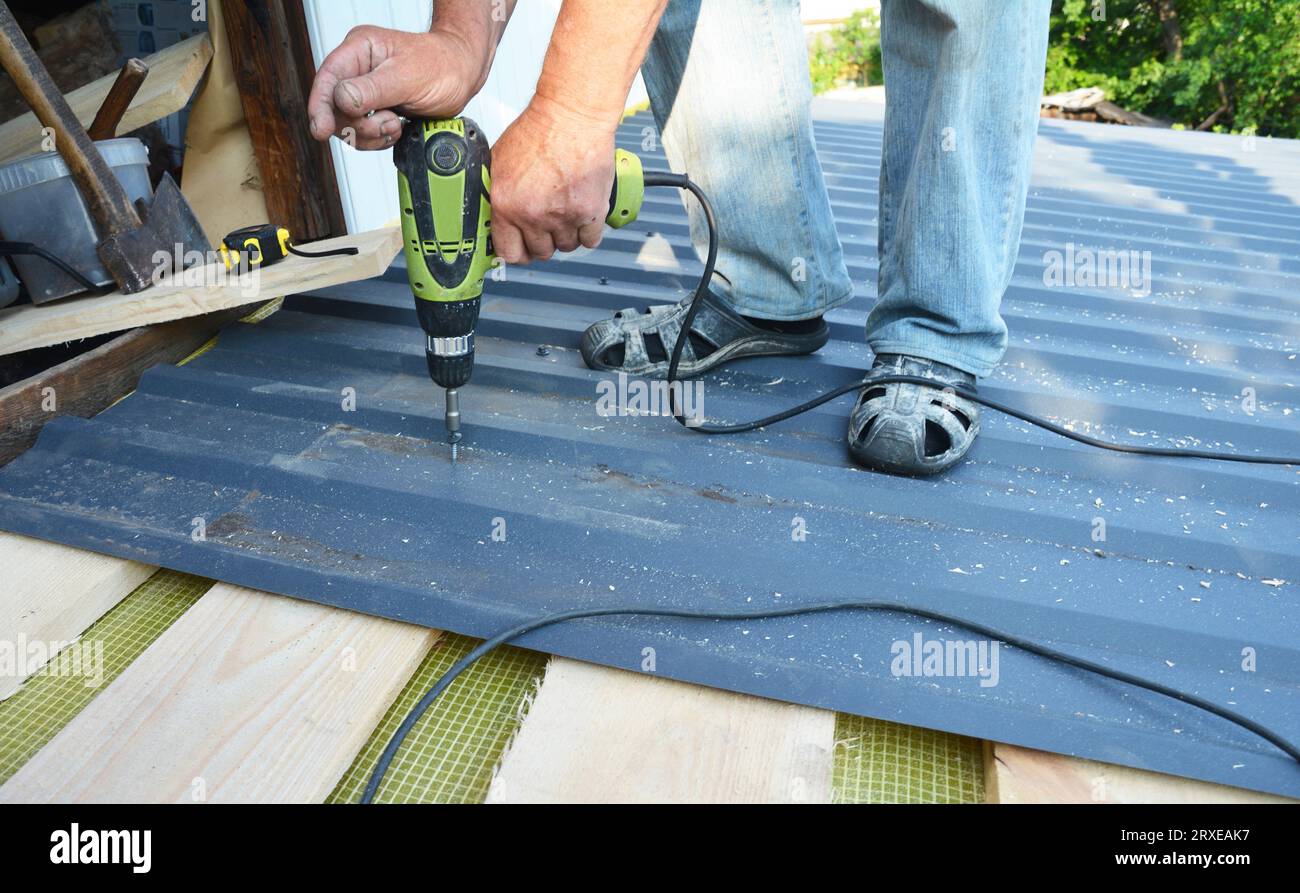 Roofing contractor installing metal roof sheets on the house rooftop ...