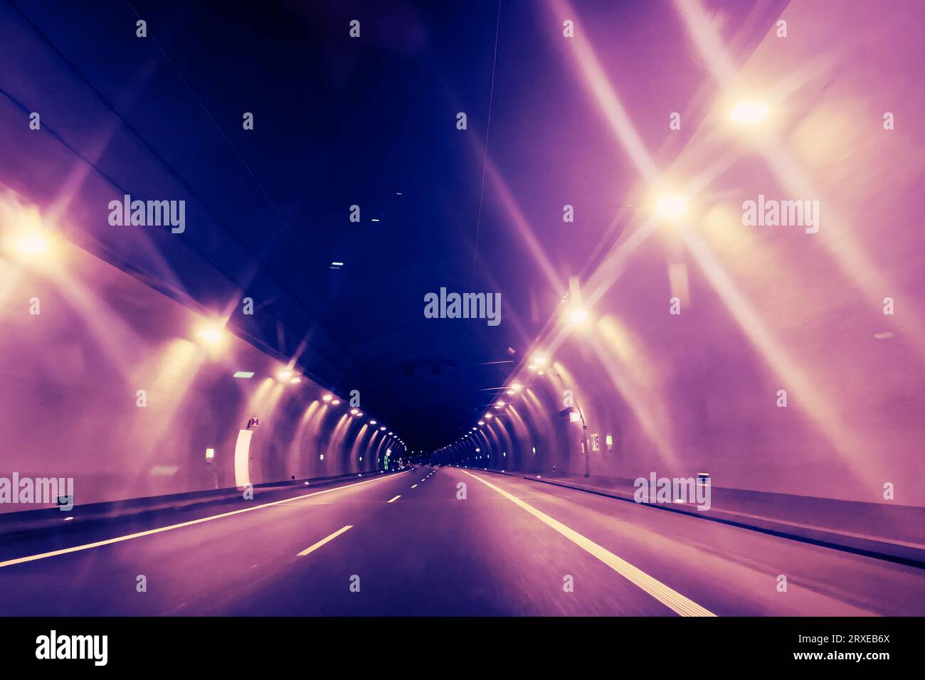 Illuminated underground highway tunnel. Travel on asphalt road in ...