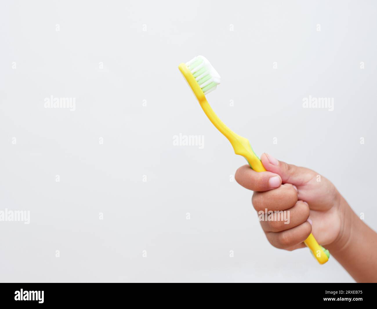 Child's hand holding a toothbrush, isolated on a white background with ...