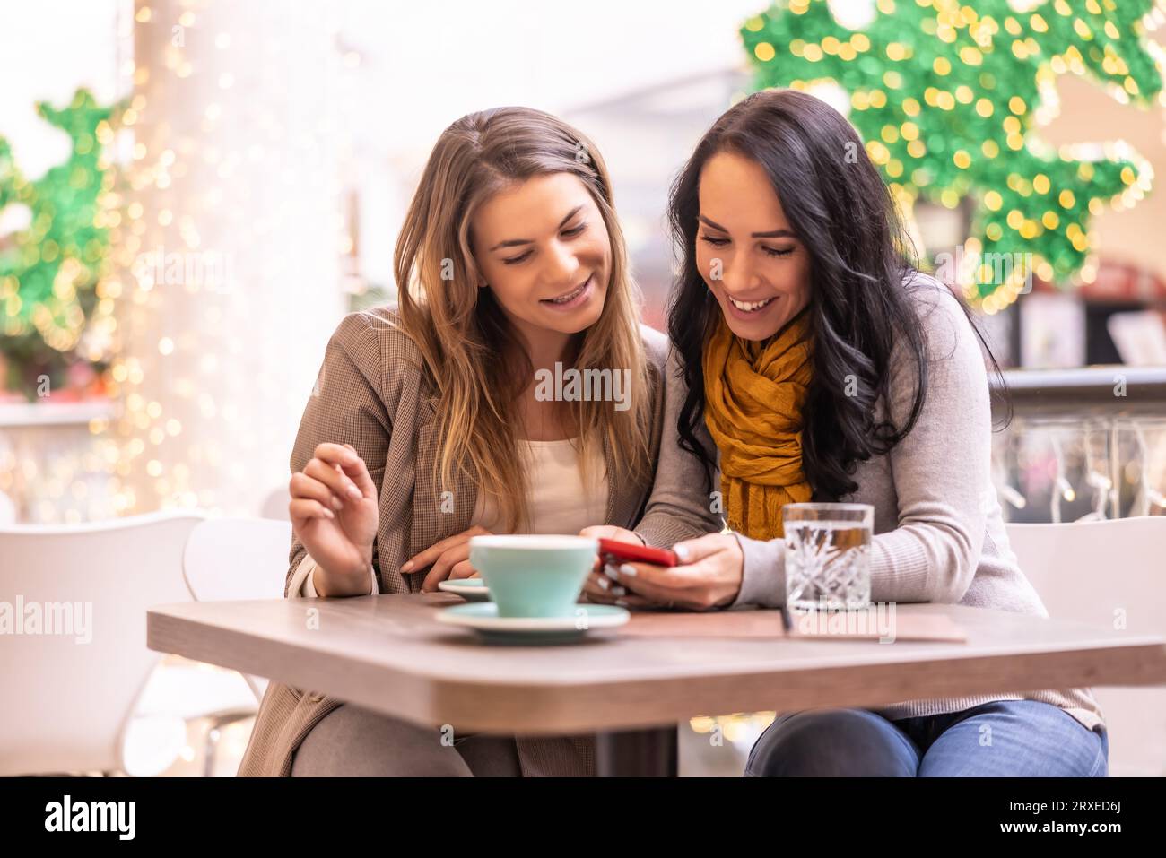 Two good-looking girls taking a coffee break during Christmas shopping ...