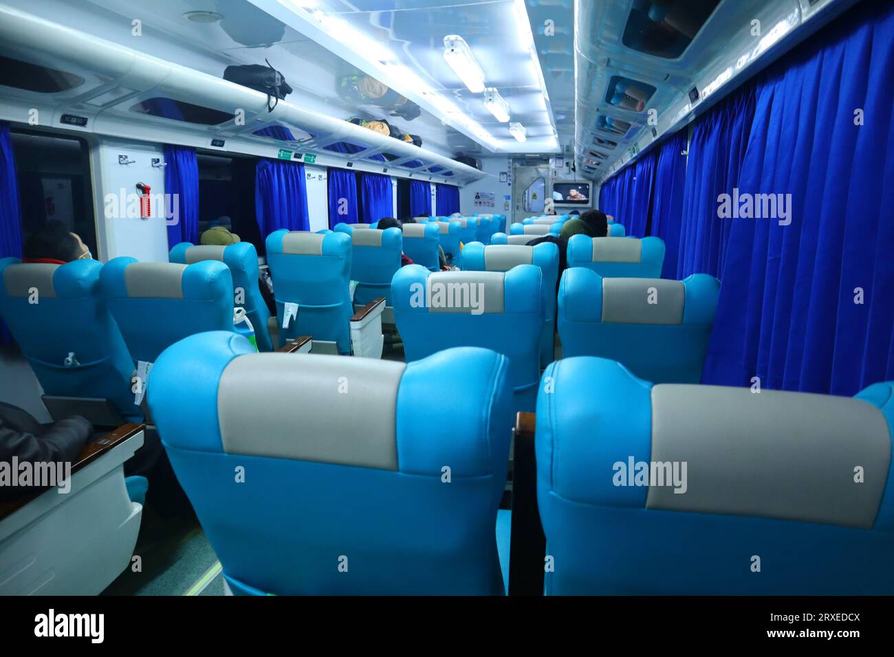 Executive class train interior with blue seats, armrests, luggage racks ...