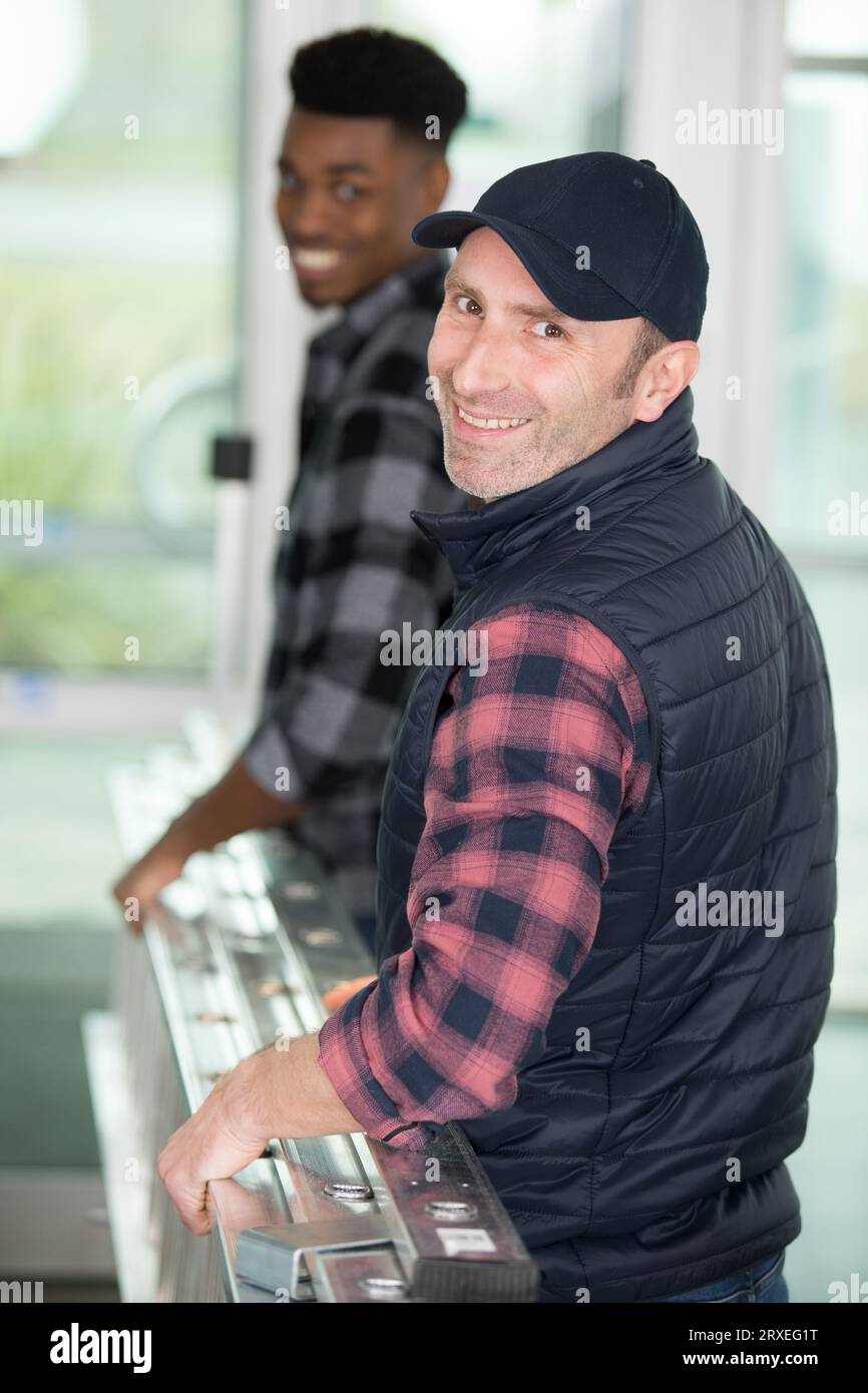 2 construction workers carrying metal trays Stock Photo - Alamy