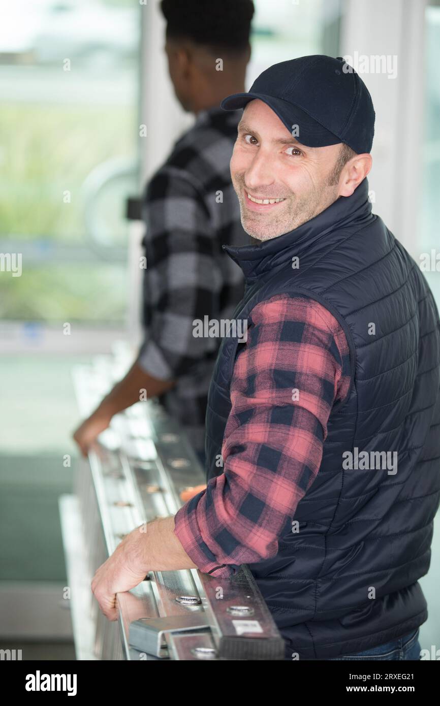 two men carrying a ladder Stock Photo - Alamy