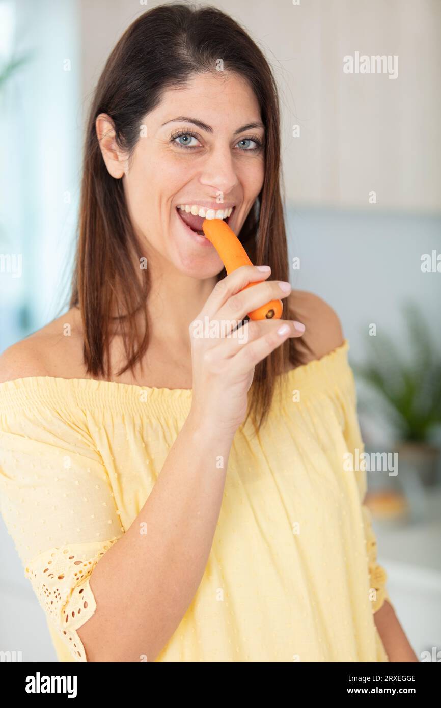 attractive woman biting into a raw carrot Stock Photo - Alamy