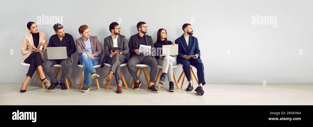 Business people sitting in row looking to side Stock Photo - Alamy