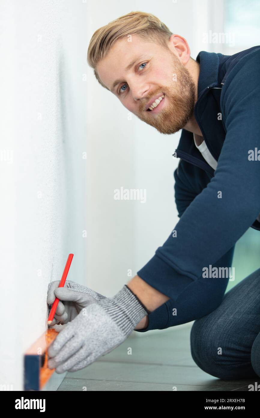 builder using a spirit level to mark a wall Stock Photo - Alamy