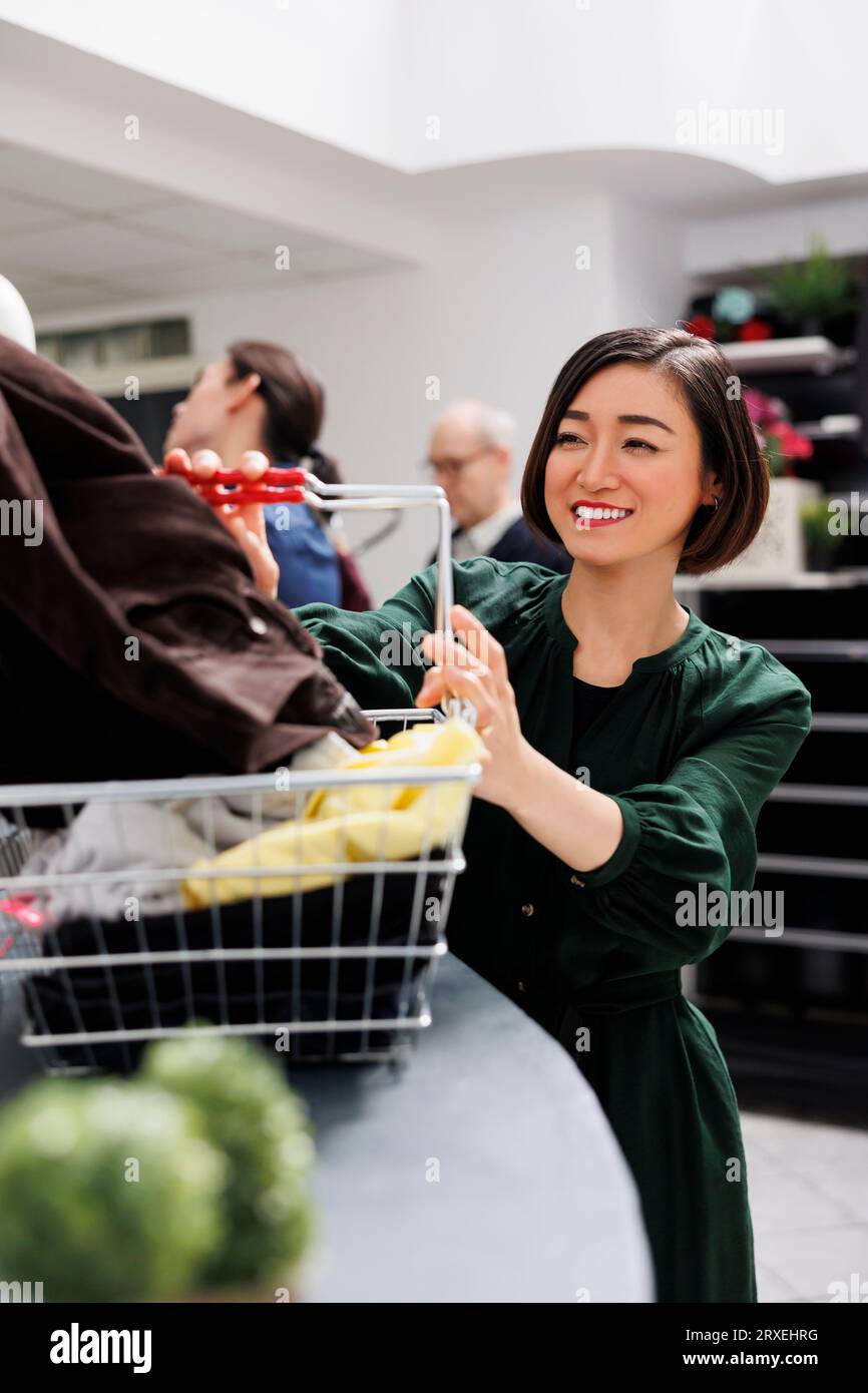 Happy smiling young female customer standing in clothing store giving ...