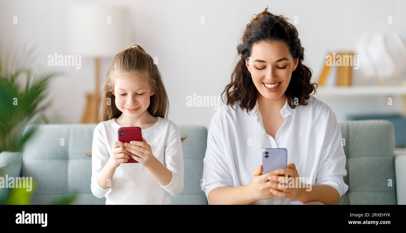 Happy family. Young mother and daughter using phones Stock Photo - Alamy