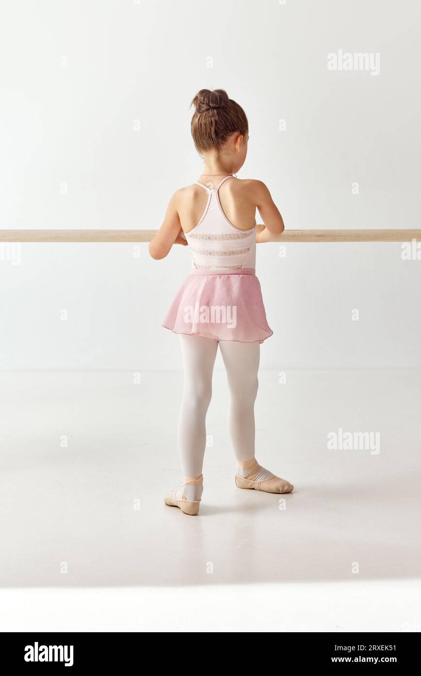Rear view portrait of small adorable ballerina dancer girl in rose tutu ...