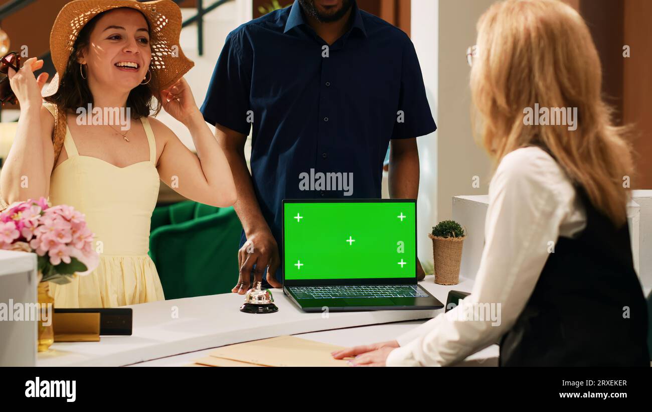 Hotel worker welcoming guests at reception, using greenscreen template ...