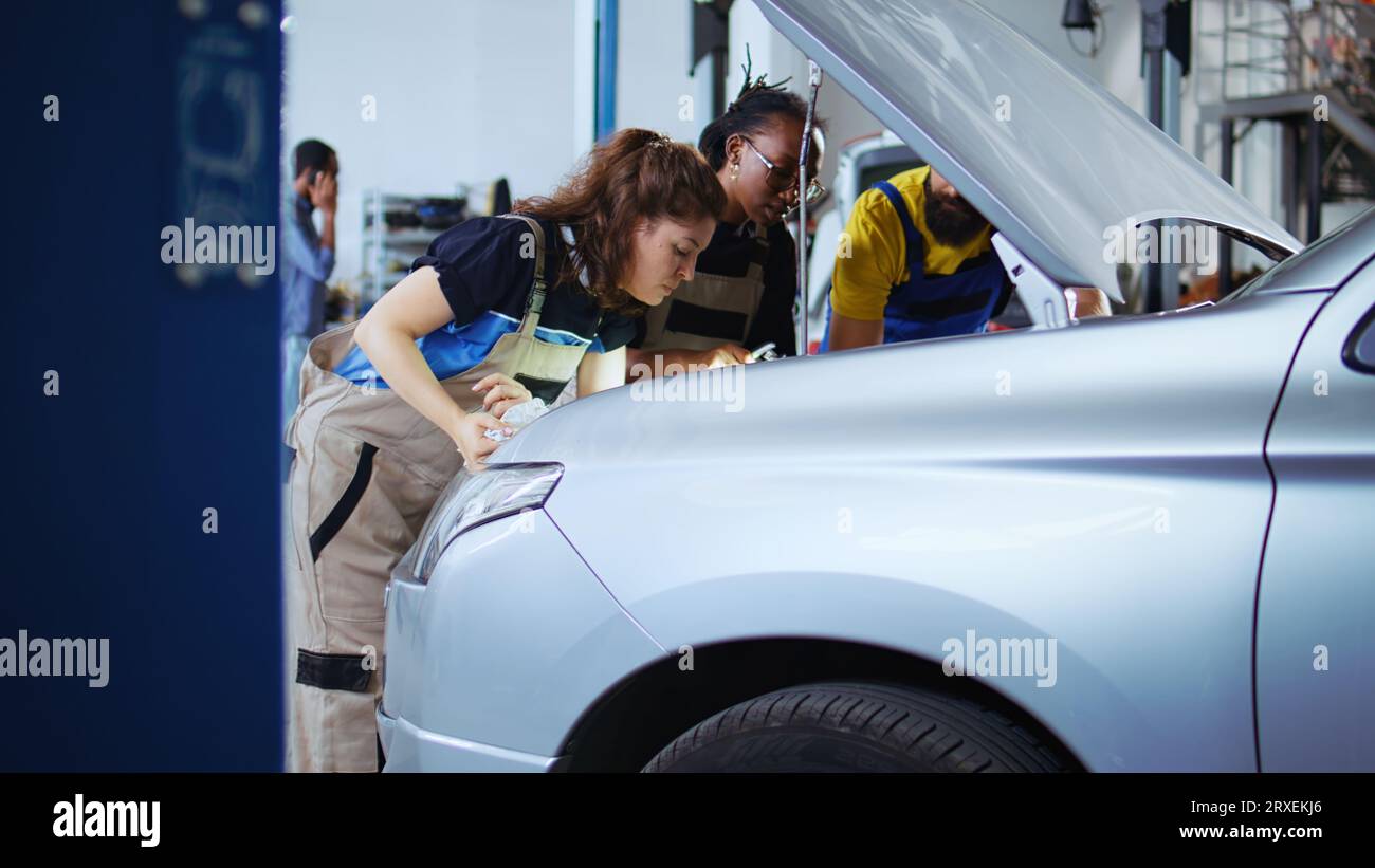 Team of mechanics in car service using inspection lamp to fix ...