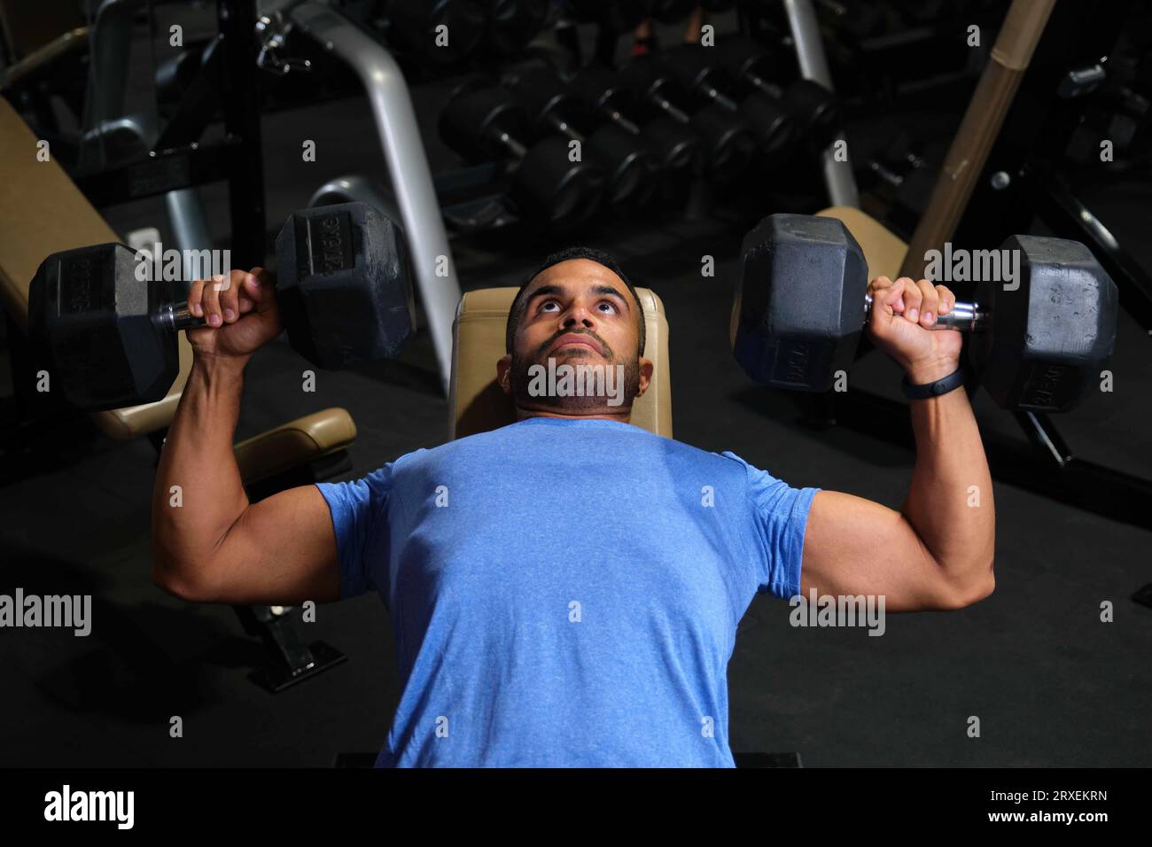Strong Hispanic man doing dumbbell chest press at a gym Stock Photo - Alamy
