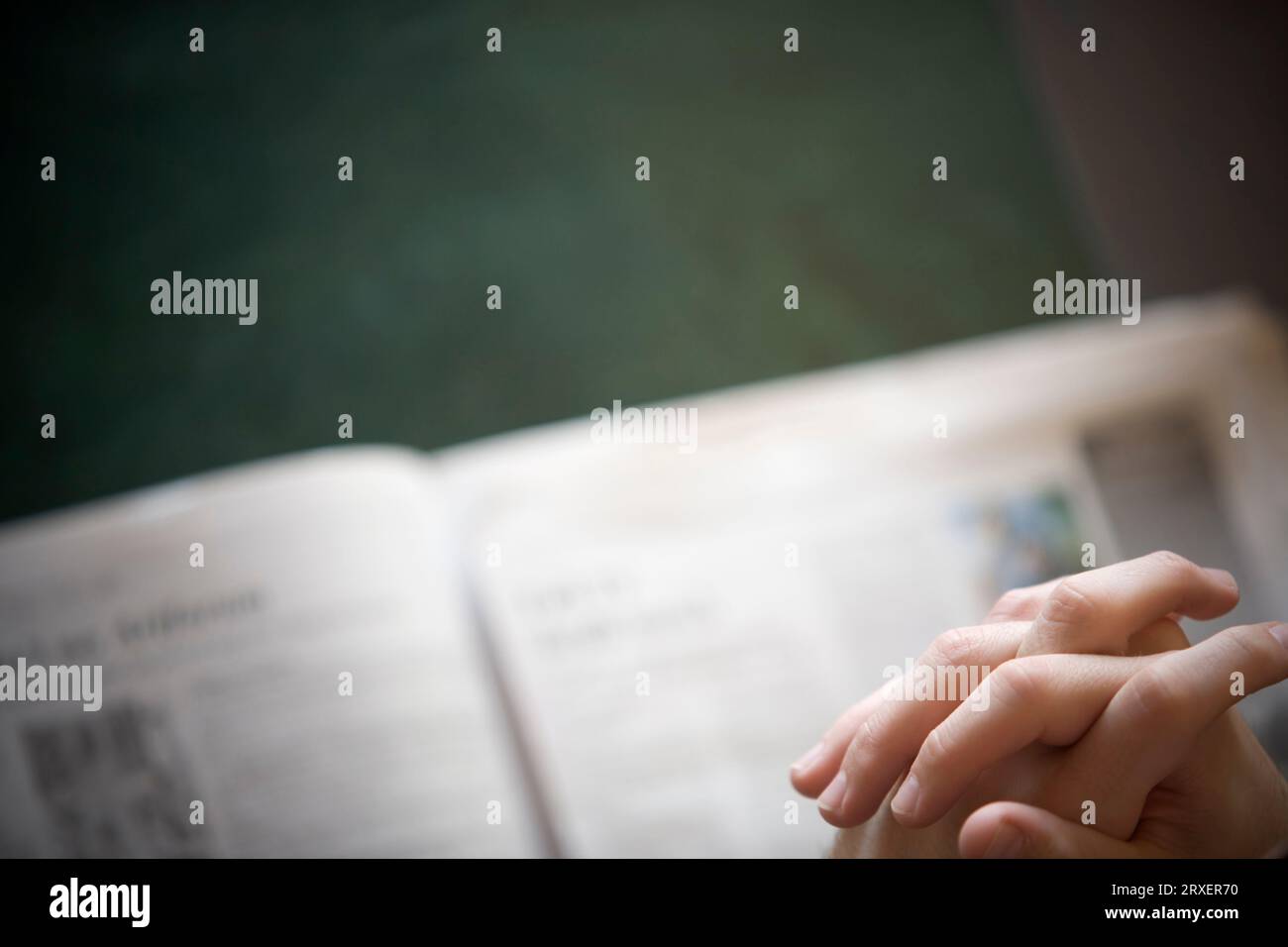 Hands folded over a open newspaper Stock Photo - Alamy