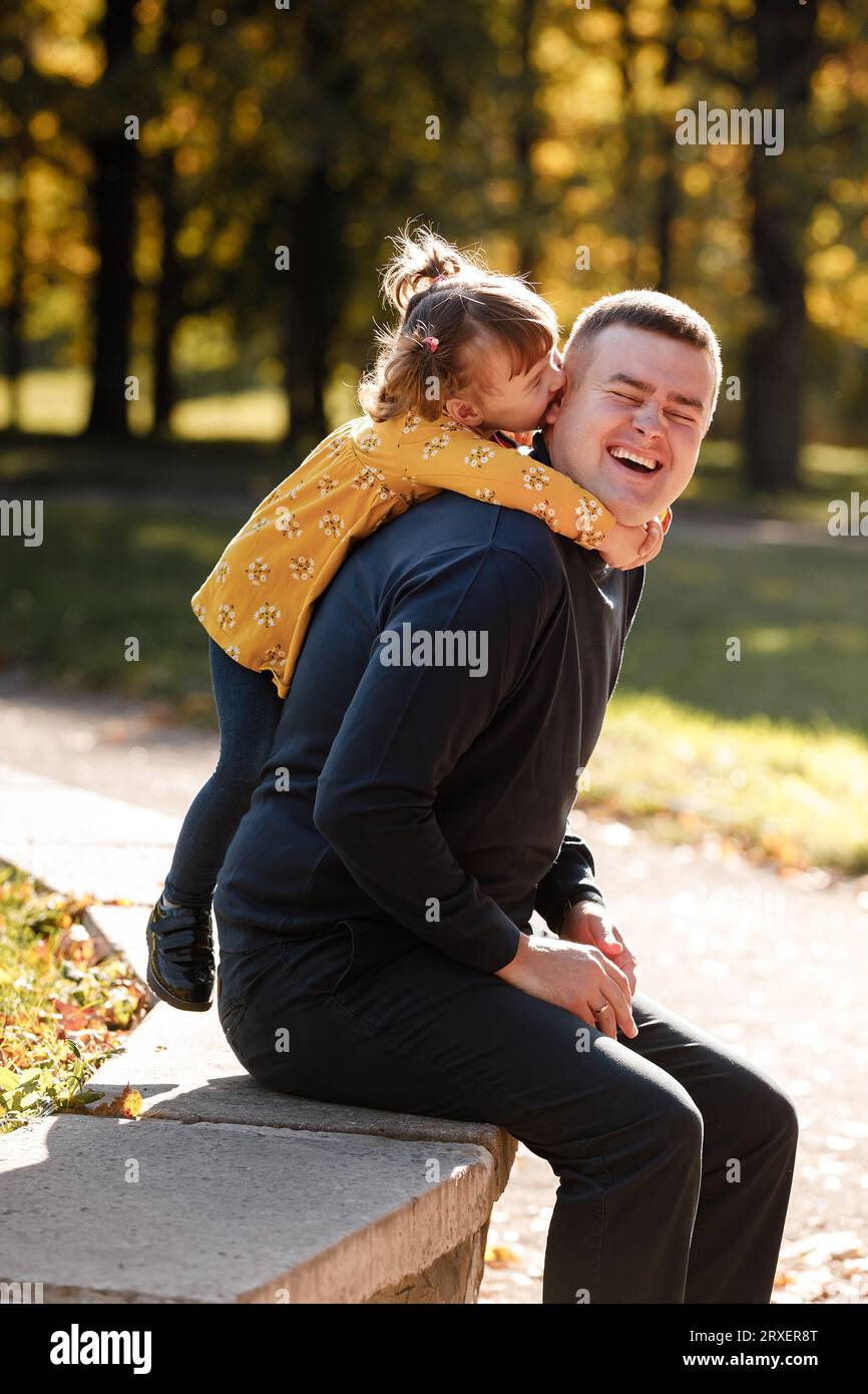 Joyful dad hugs his little smiling daughter. Single daddy and child ...