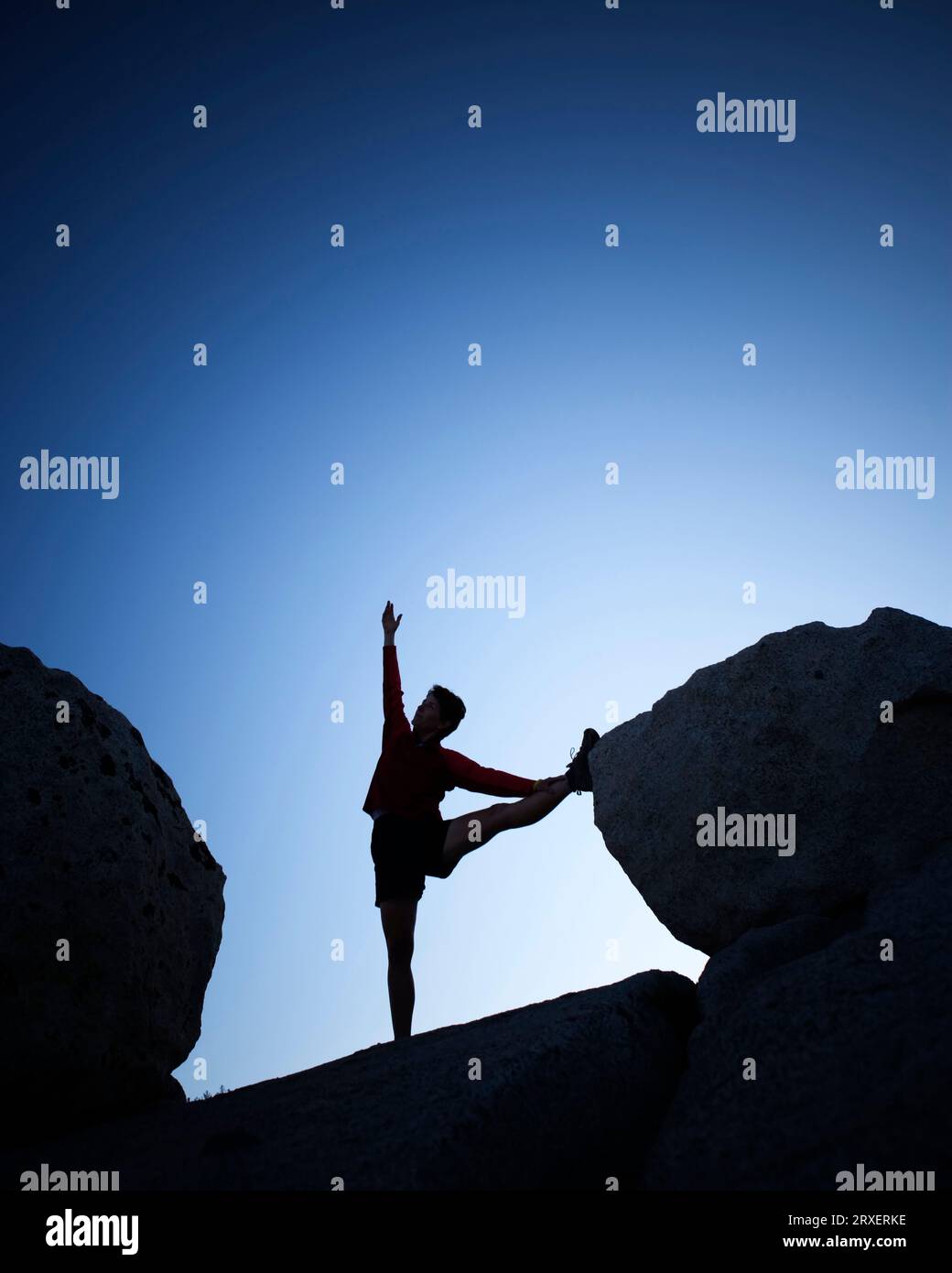 A silhouette of a person stretching between two large rocks Stock Photo ...