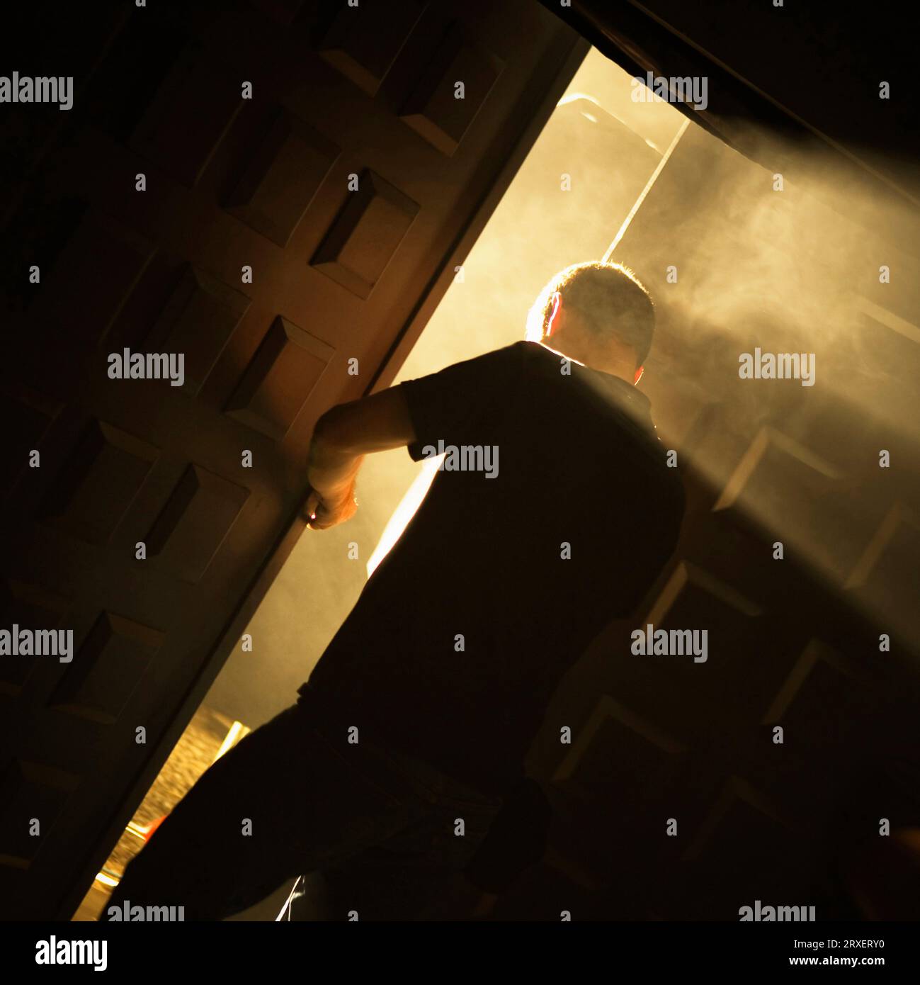 Silhouette of a man exiting a doorway with light rays Stock Photo - Alamy