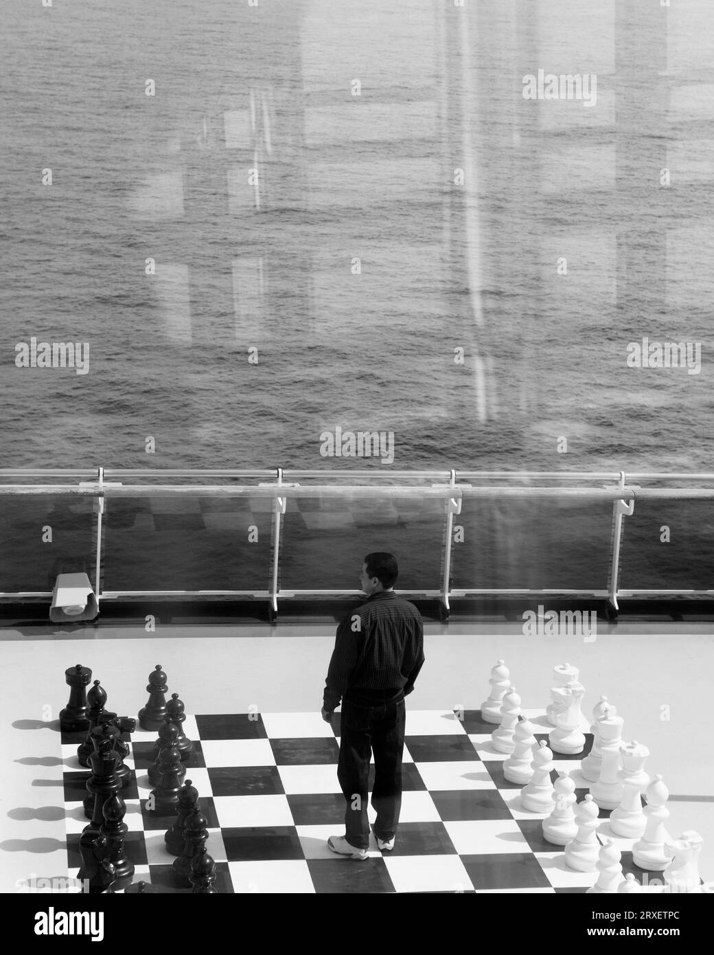 Elevated rear view of a person standing on a giant chess set on the ...