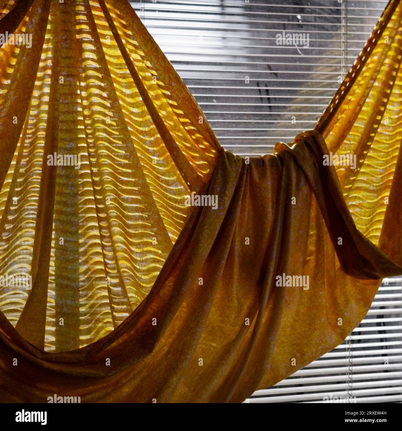 Gold colored cloth hanging in front of window blinds Stock Photo - Alamy