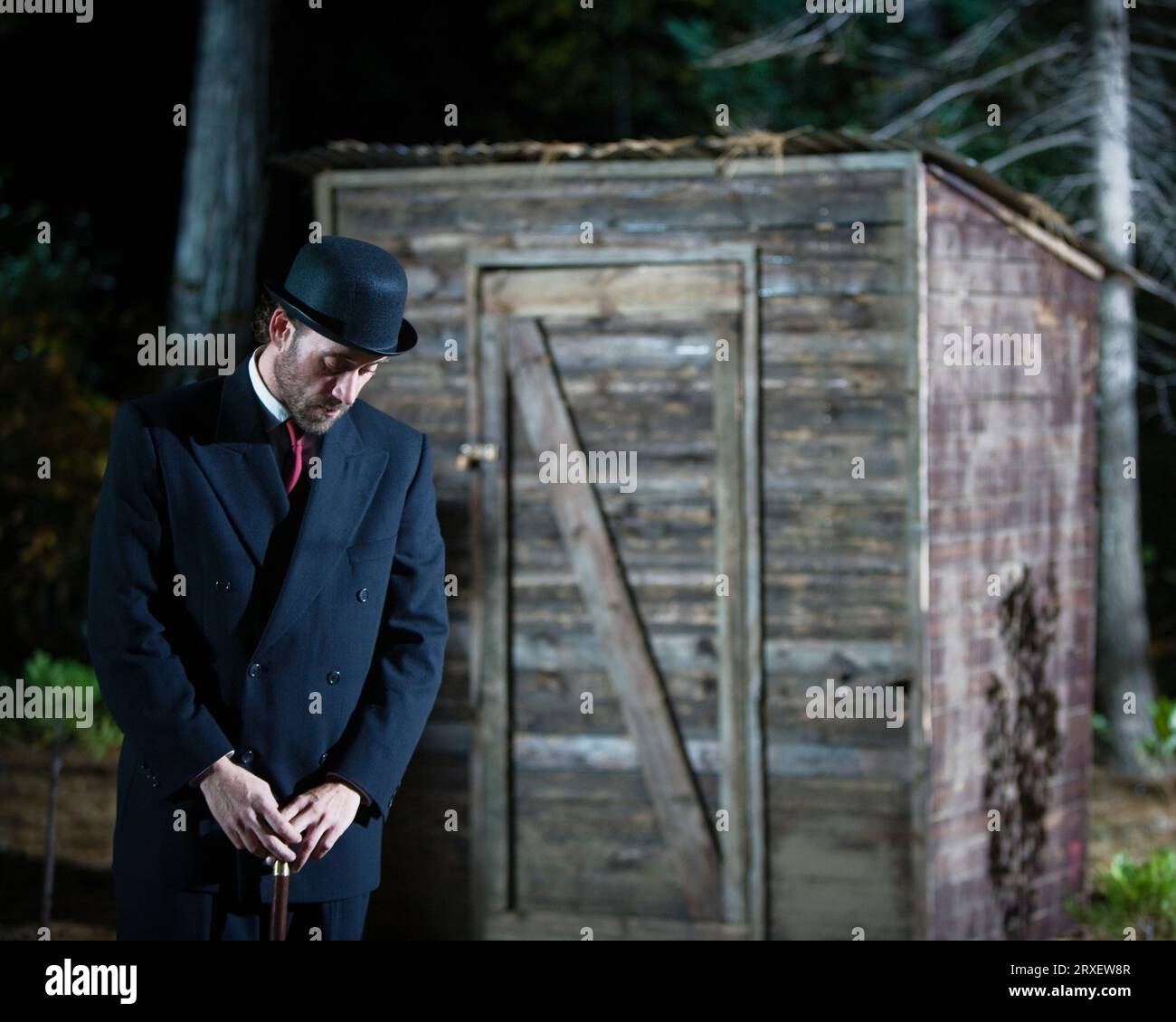 A man standing infront of a wooden shed at night Stock Photo - Alamy