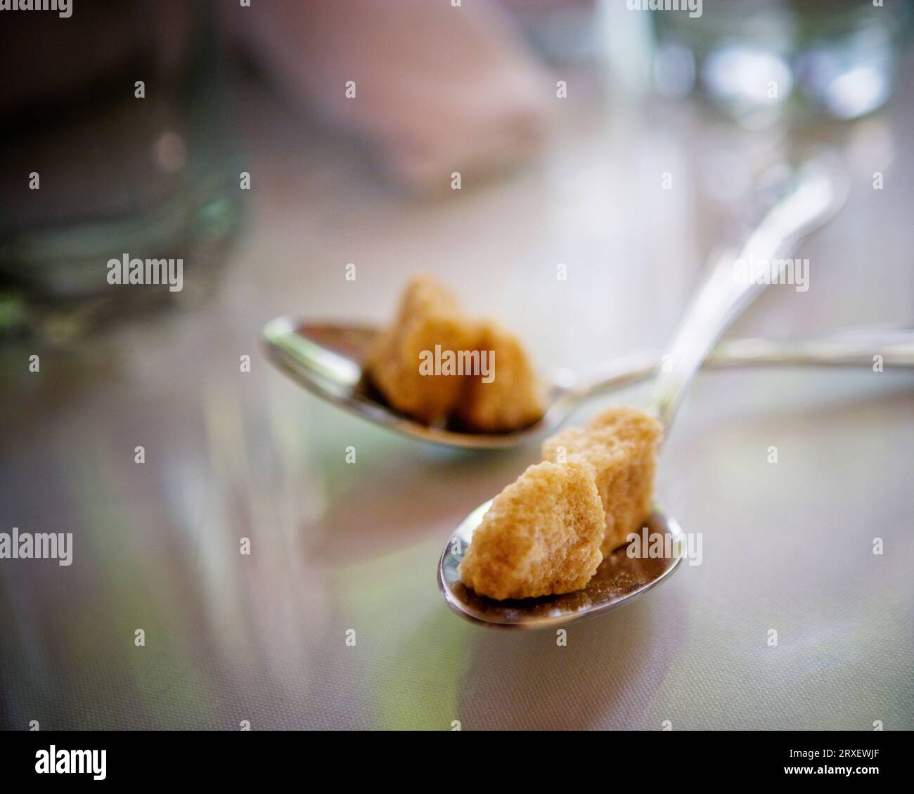 Two spoons with lumps of raw sugar Stock Photo - Alamy
