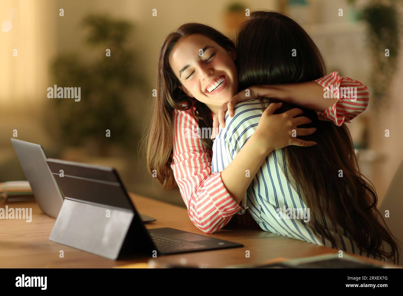 Two women hugging in the night at home celebrating success Stock Photo ...