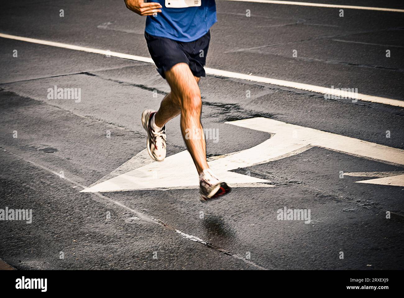 A man in blue shirt running past white painted arrows on the road ...