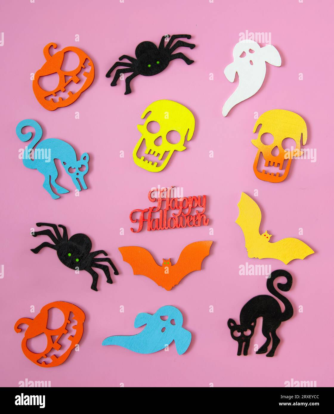 Wooden coloured cutouts of halloween symbols shot from above on a pink ...