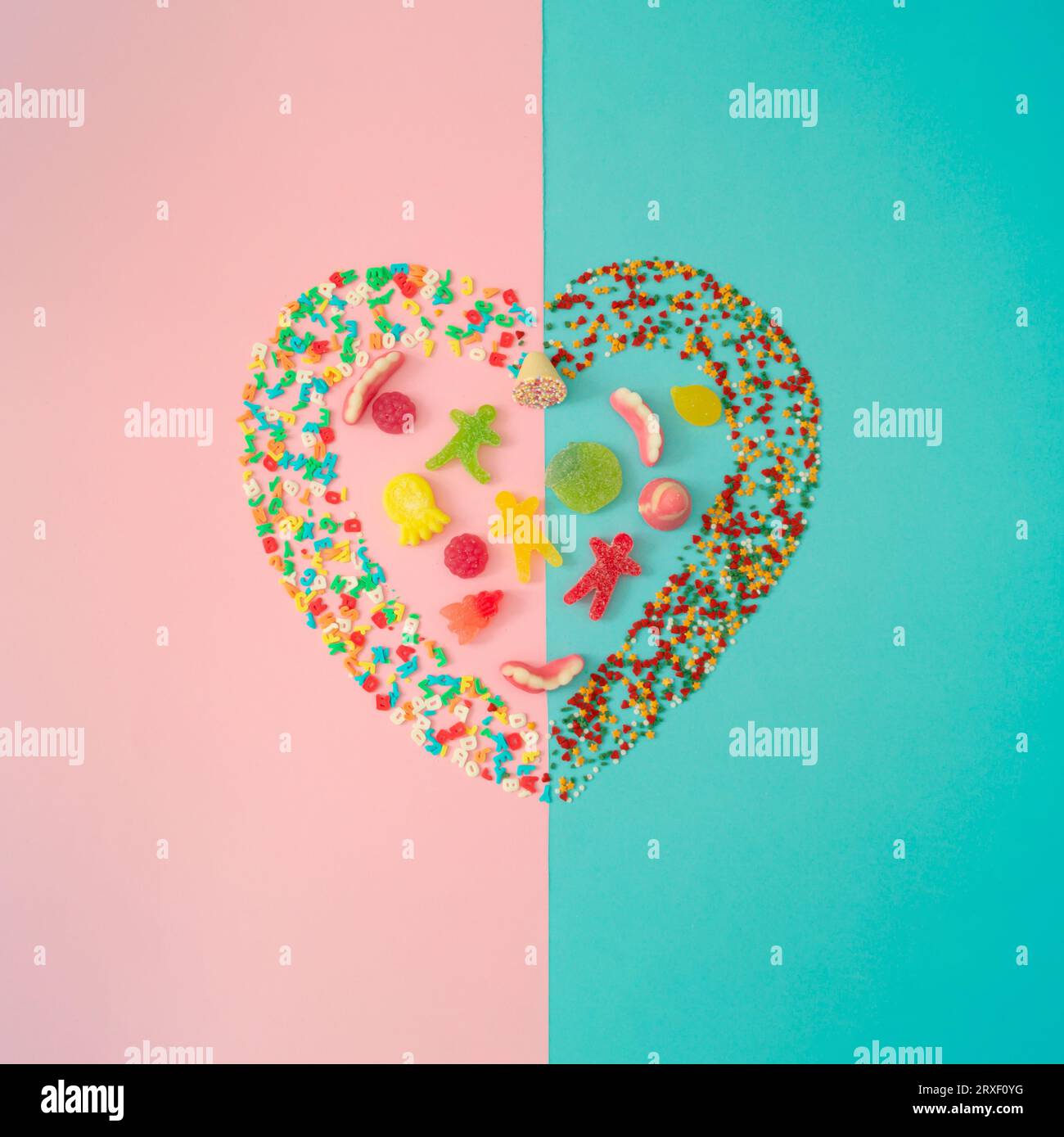 Trendy heart made of gummy candies and sprinkles on pastel pink and ...