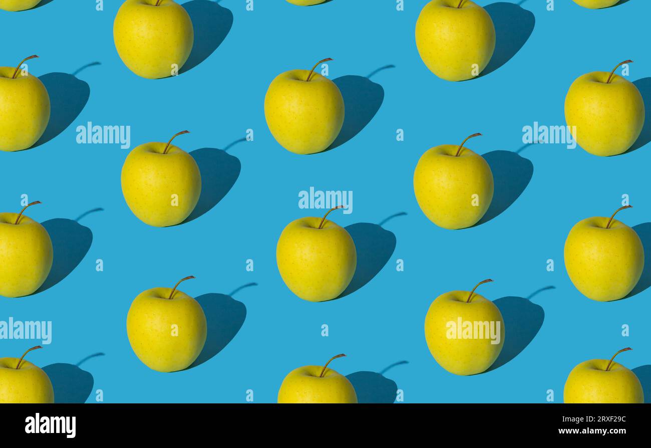 Trendy fruit pattern made of yellow apples on light pastel blue ...