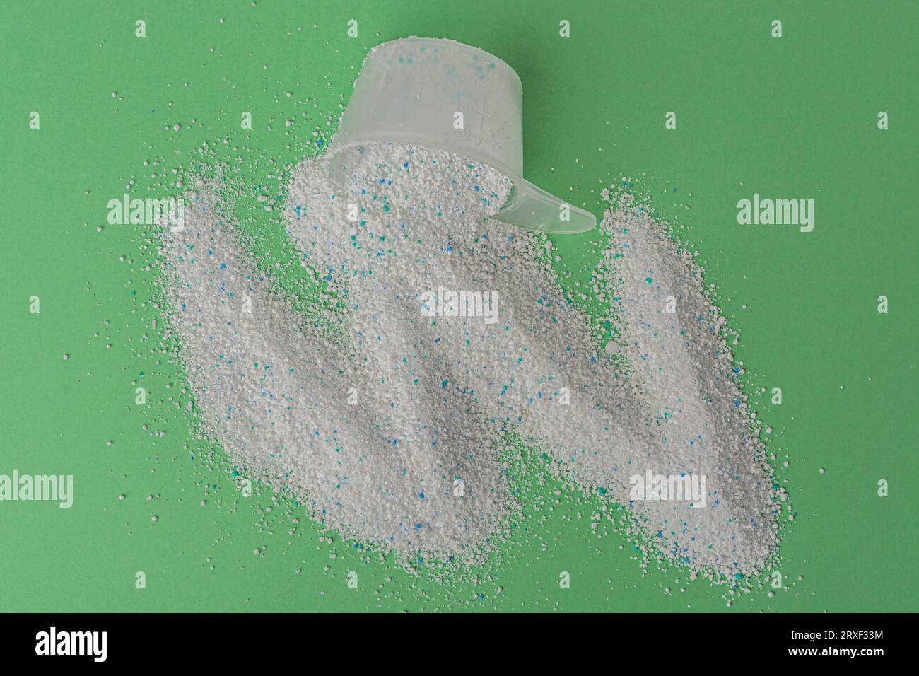 Detergent washing powder with measuring spoon on green background Stock ...