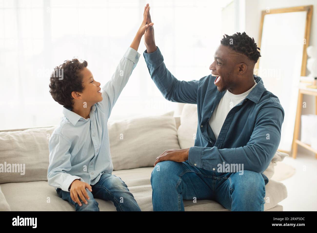 Cheerful Black Dad and His Son Clapping Palms Together Indoor Stock ...