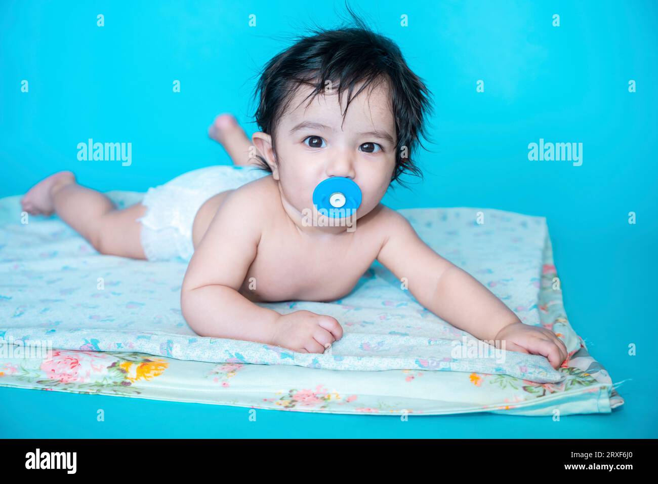 Small six months old cute indian baby boy wearing diaper lying on floor ...
